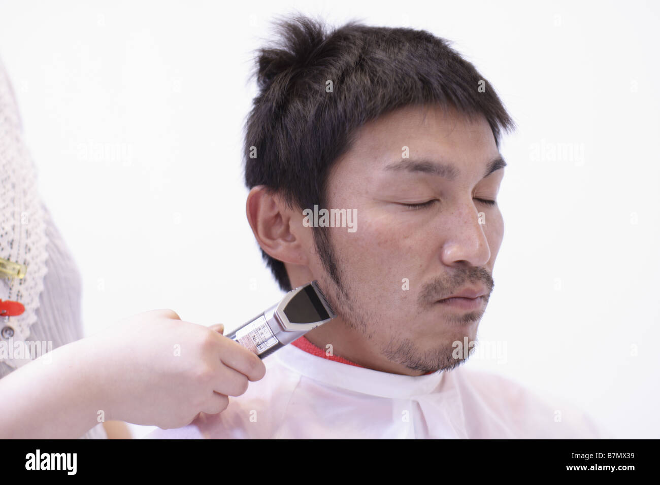 Hairdresser Shaving Man's Face With Electric Razor Stock Photo - Alamy