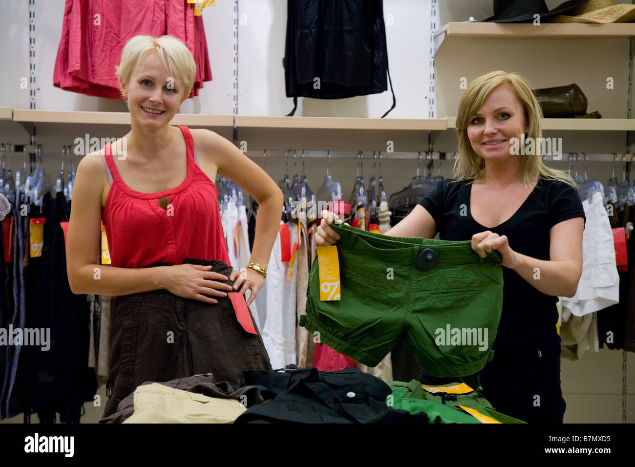 Two women comparing different clothes in shop Stock Photo - Alamy