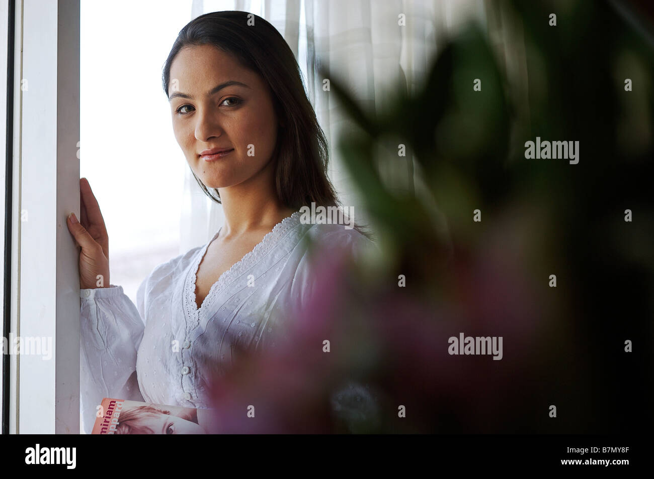 Portrait of a woman standing by a window Stock Photo - Alamy