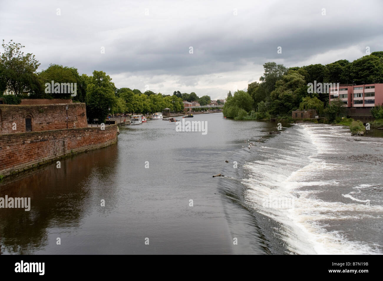 The River Dee and weir with suspension bridge in Chester, England Stock ...