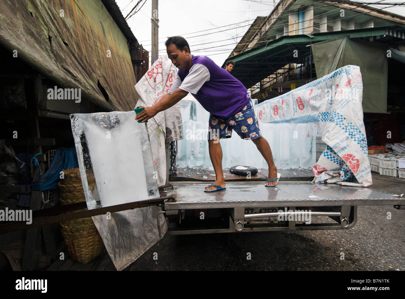 Man delivering cool storage ice blocks Pak Khlong Talad fresh fruit and ...