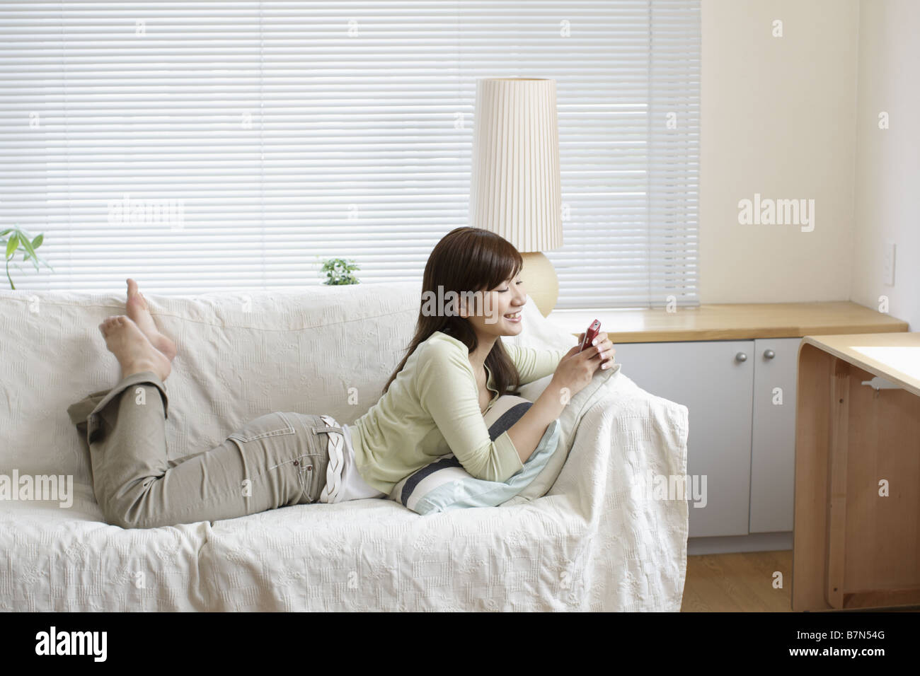 Woman Lying on a Sofa Holding a Cell-Phone Stock Photo - Alamy