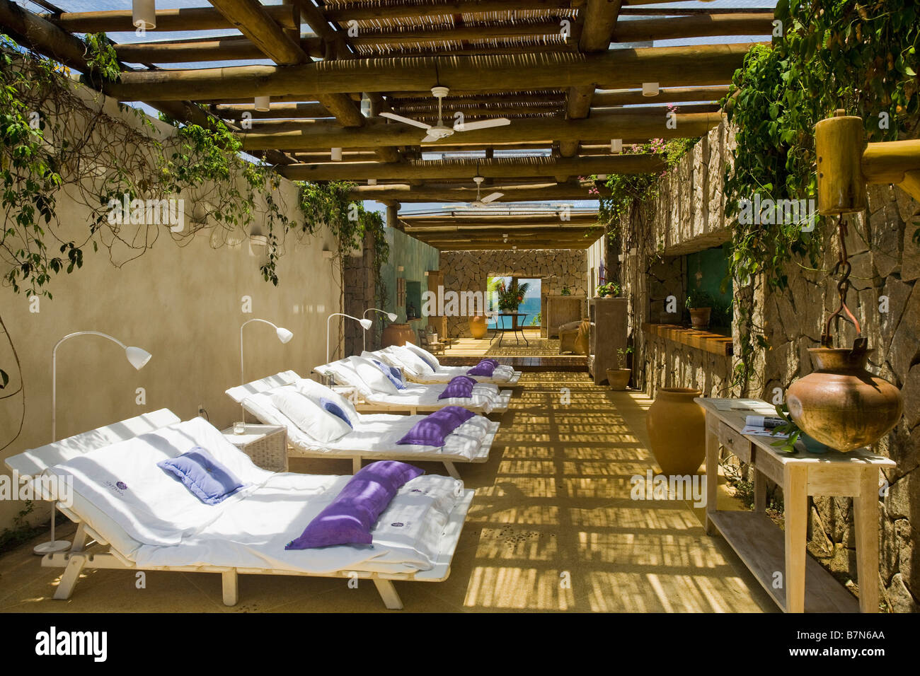 Loungers with white cushions on rustic veranda with wooden pergola in ...