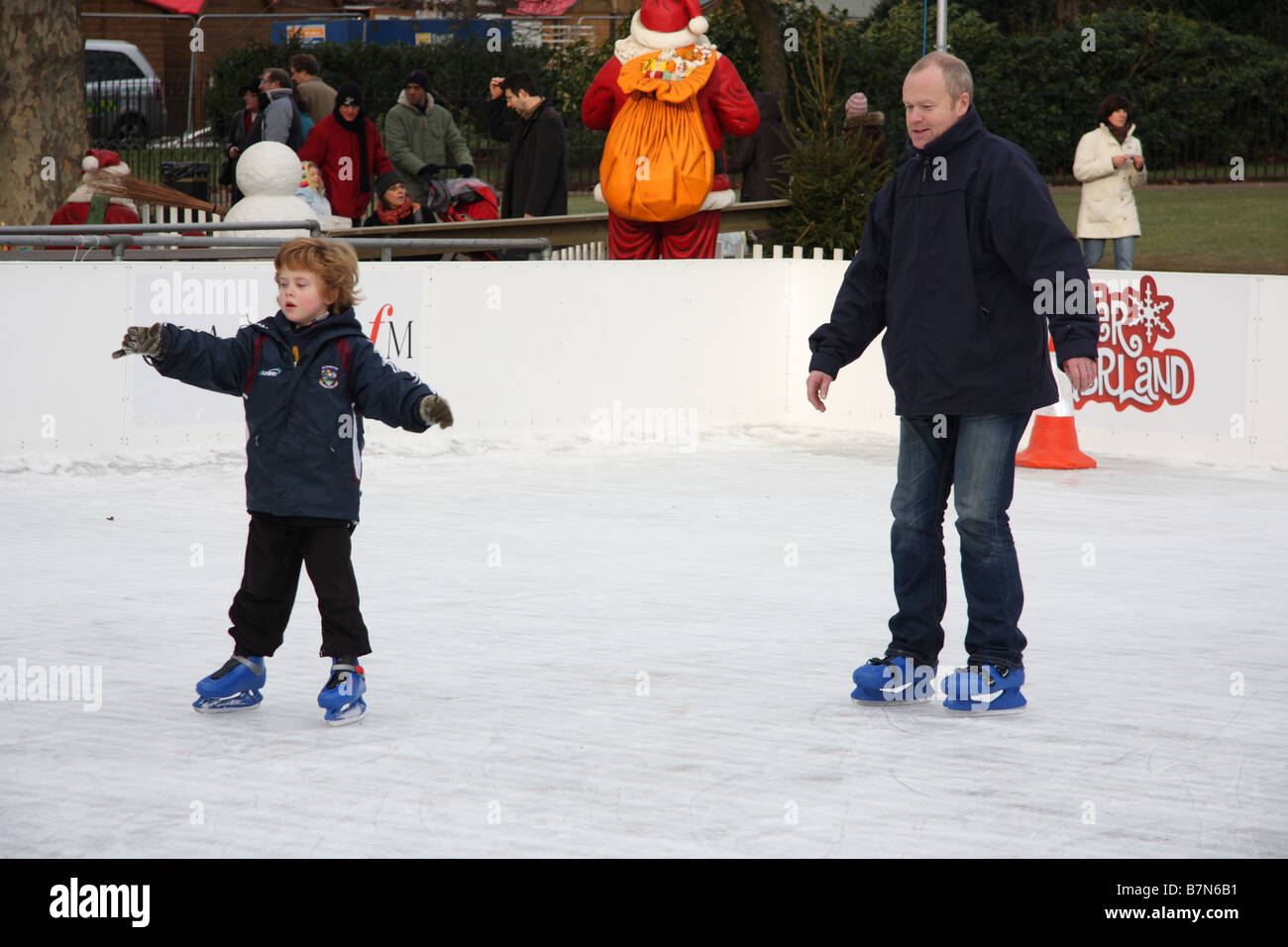 father son boy man ice skating skaters rink open air cold winter ...