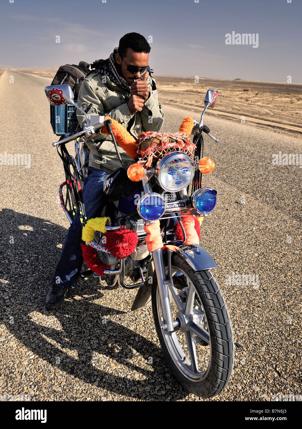 Egyptian motorbiker stopping to light cigarette in riad in western ...