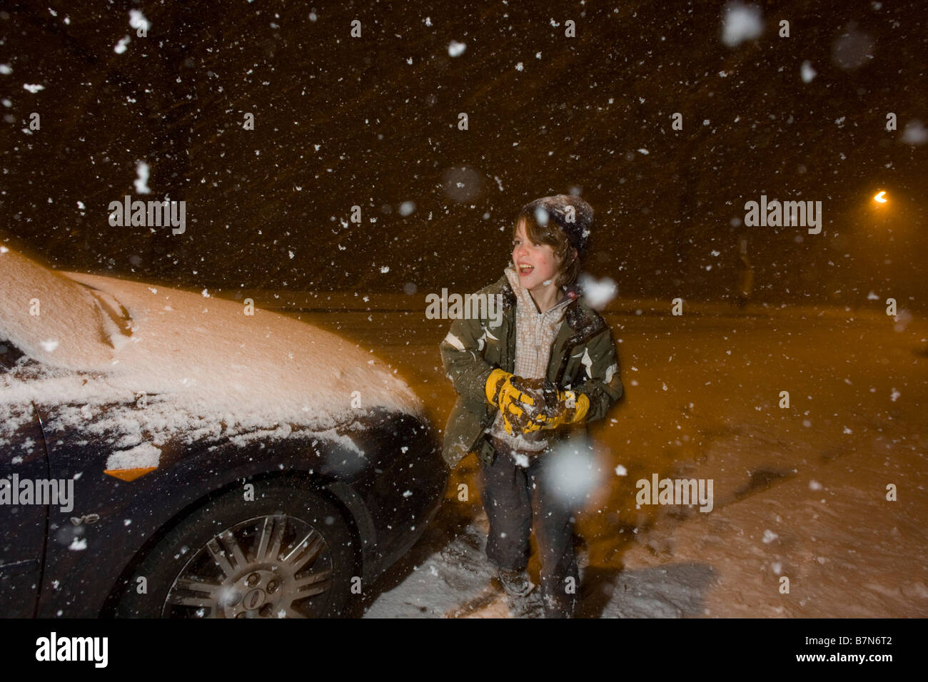 A boy plays snowballs at night during heavy snow showers in central ...