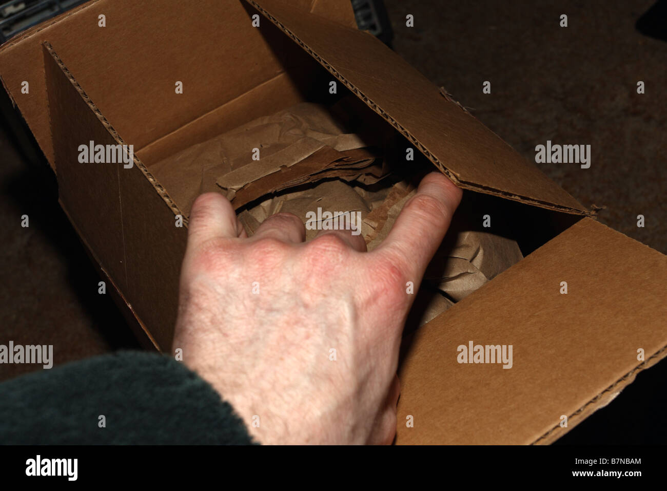 Hand opening cardboard box filled with brown paper packing Stock Photo ...