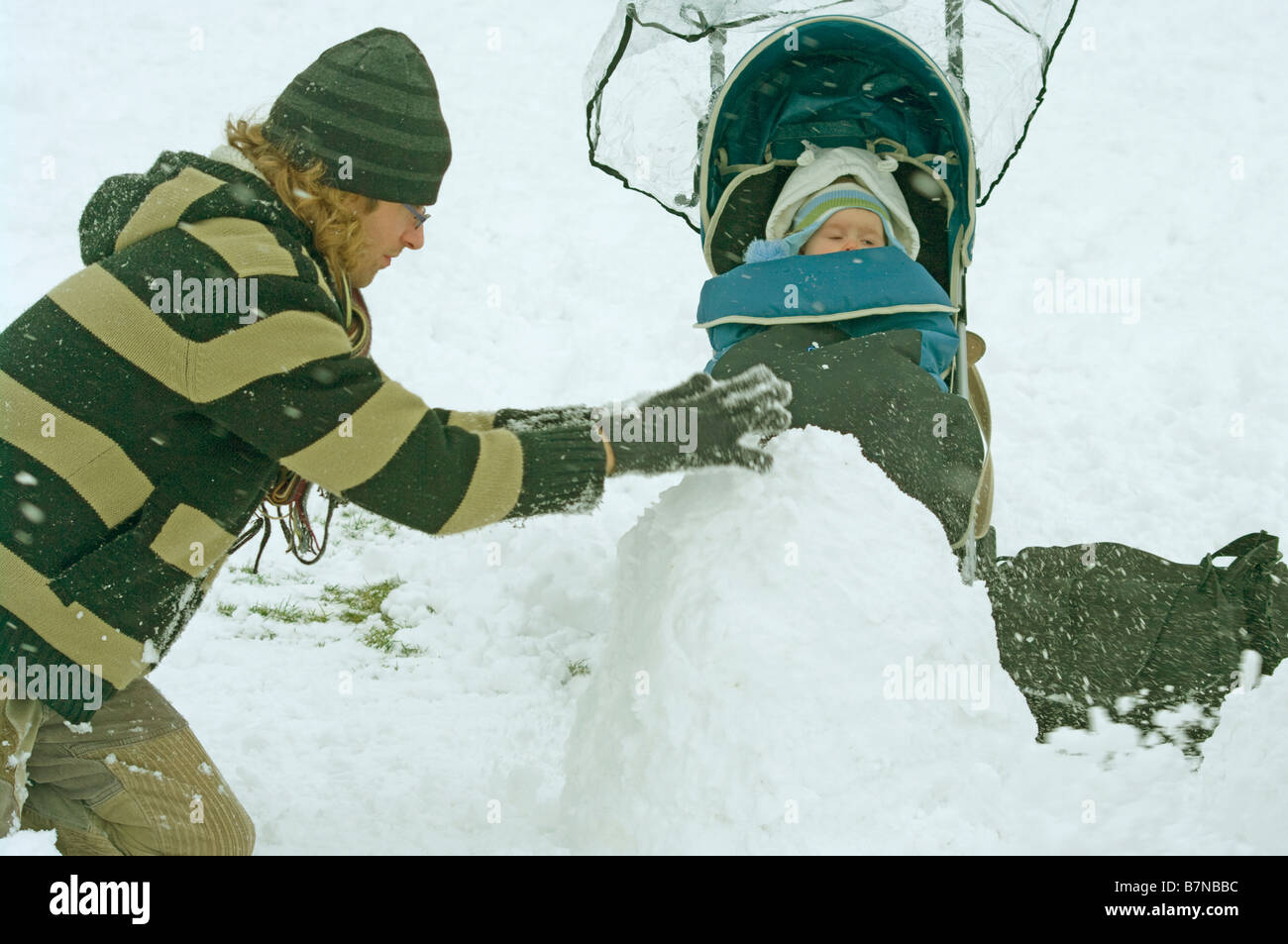 Father Man person Building a Snowman for Daughter In Her Pushchair ...
