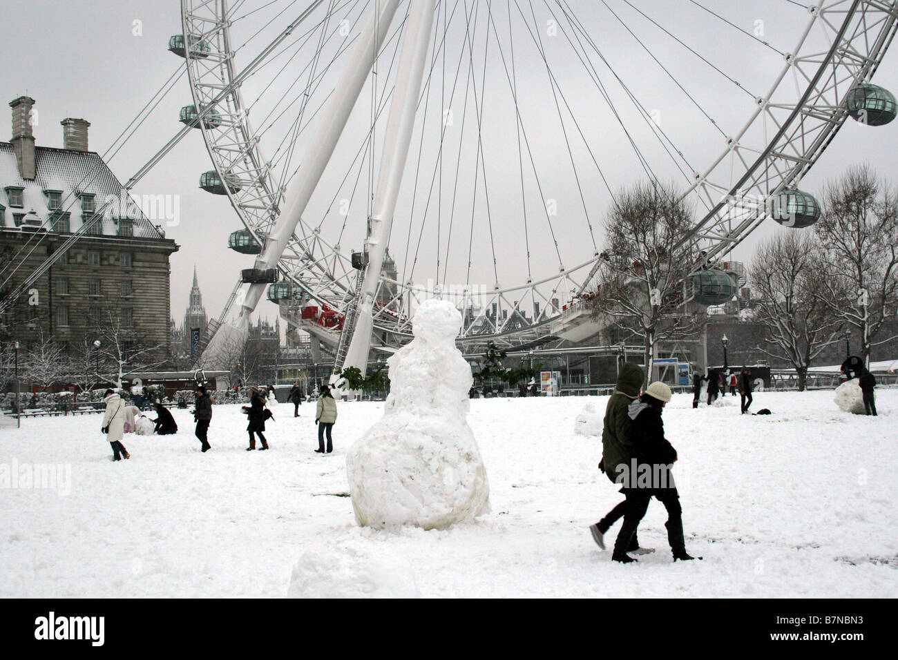 Children play in the snow in front of the London eye while making a ...