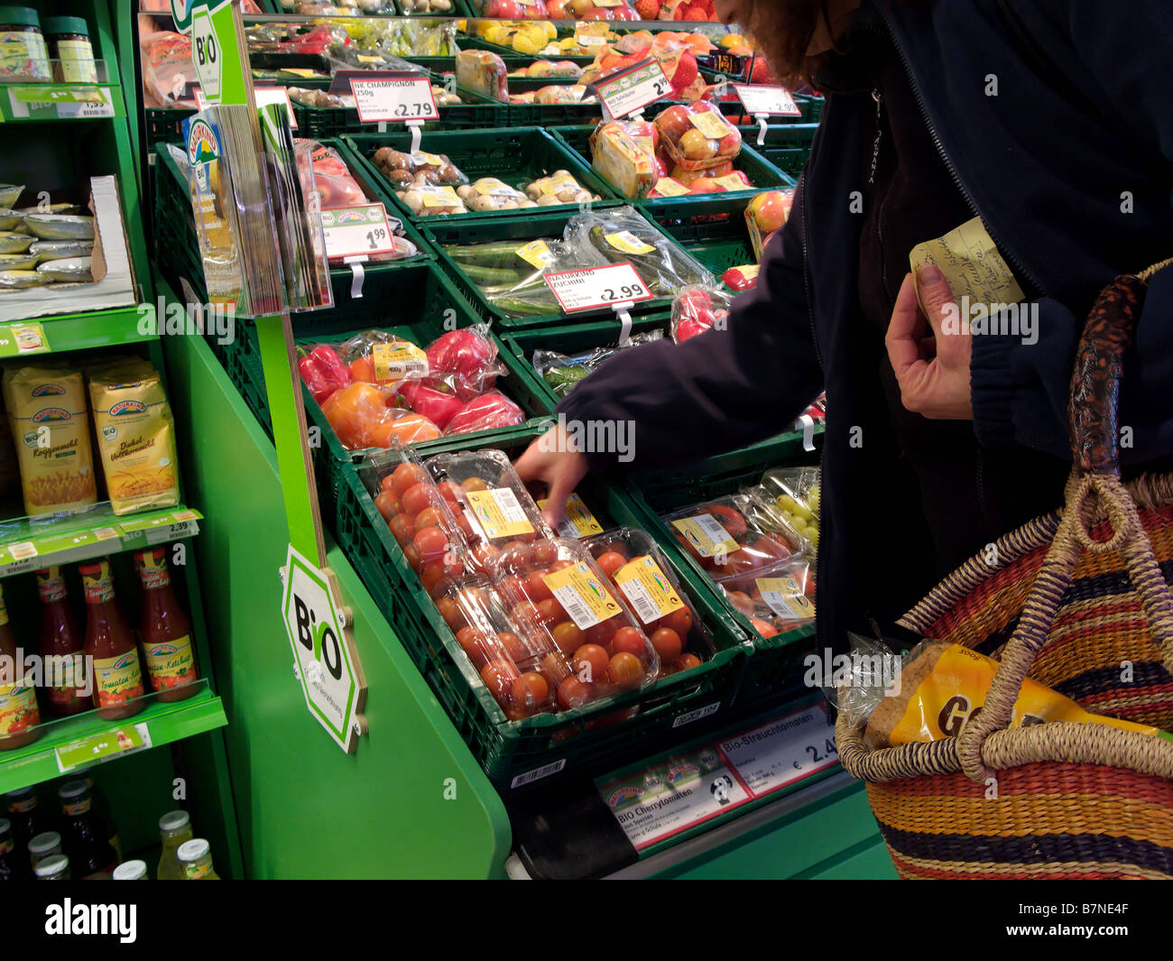 Shopper with shopping list choosing Tomatoes at a Biological Organic ...