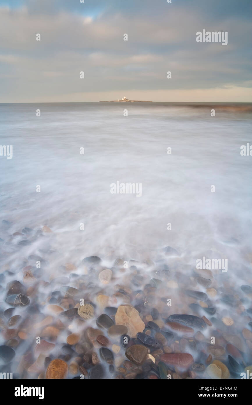 Incoming tide washing over rocks and pebbles on the beach at Low ...