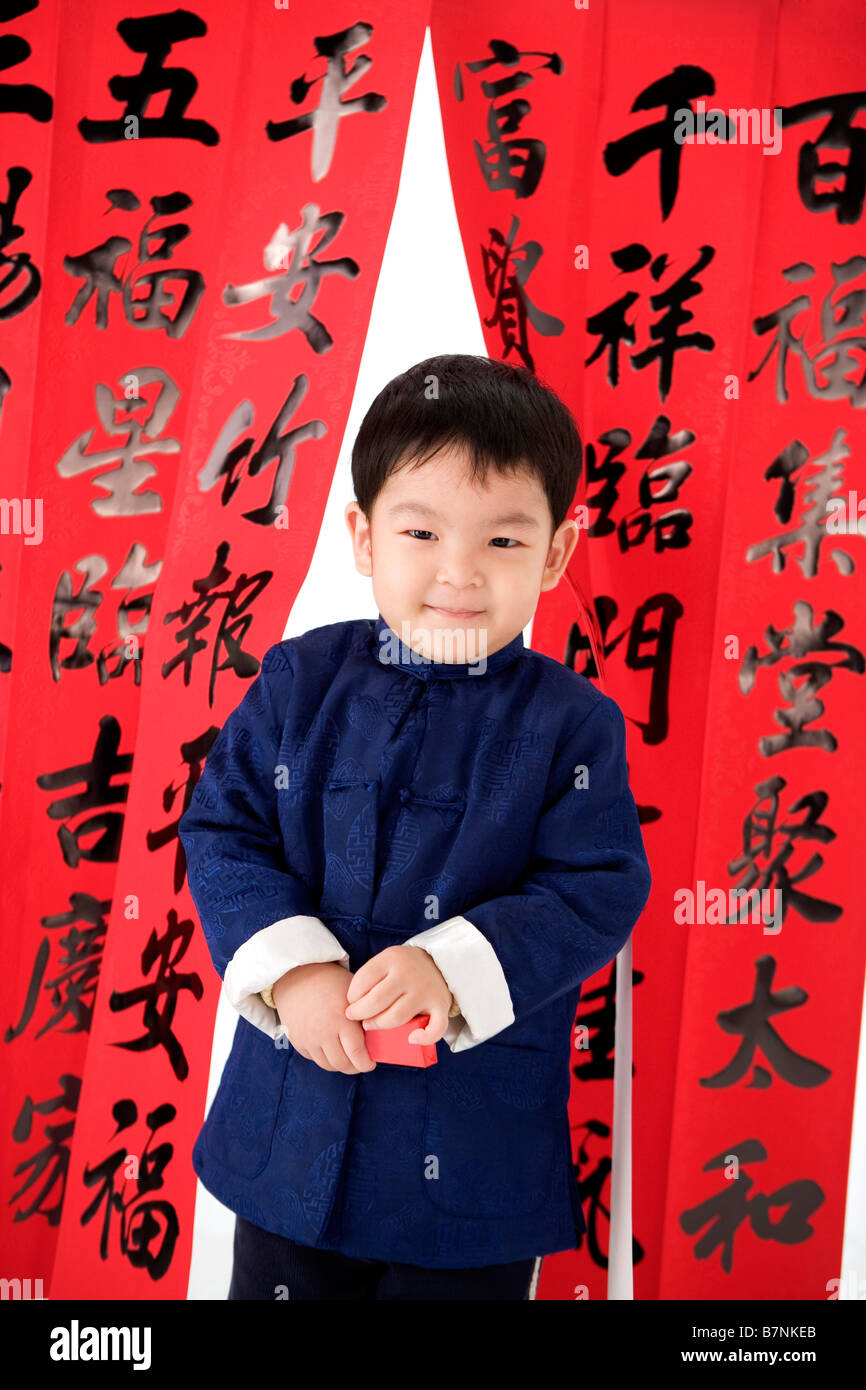 Boy in Chinese traditional clothes with red envelopes standing ...