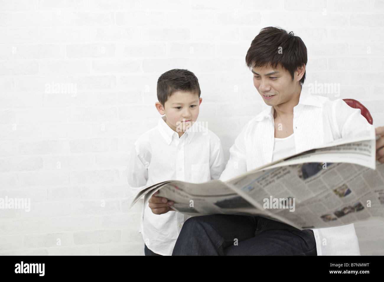 Father and son reading newspaper Stock Photo - Alamy
