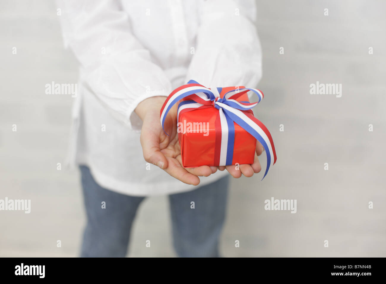 Hand is holding a gift box with a red ribbon hi-res stock photography and images - Alamy