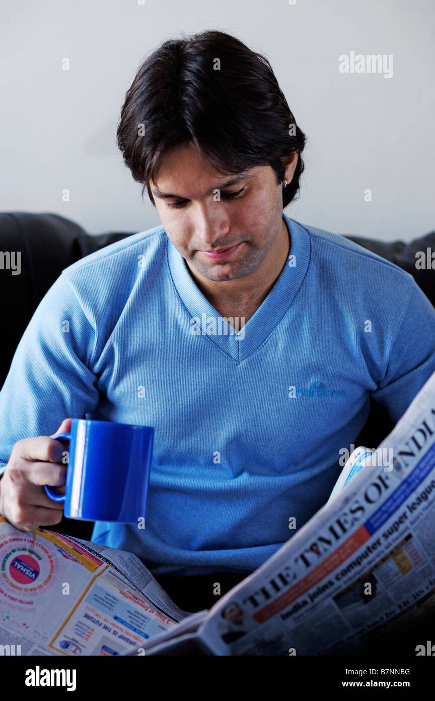 Young man reading a newspaper Stock Photo - Alamy