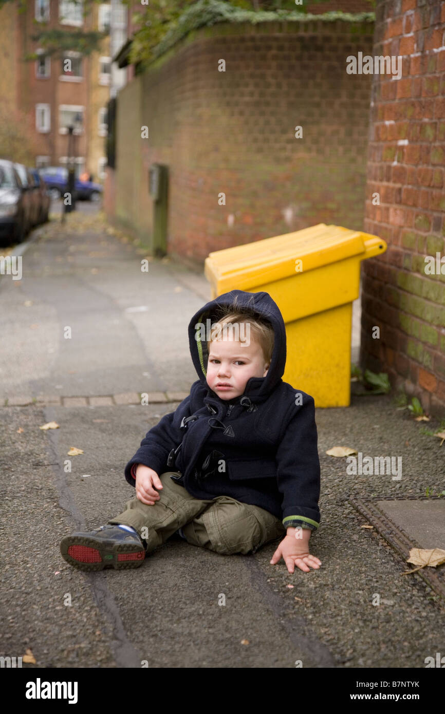 Moody boy sitting on pavement Stock Photo - Alamy