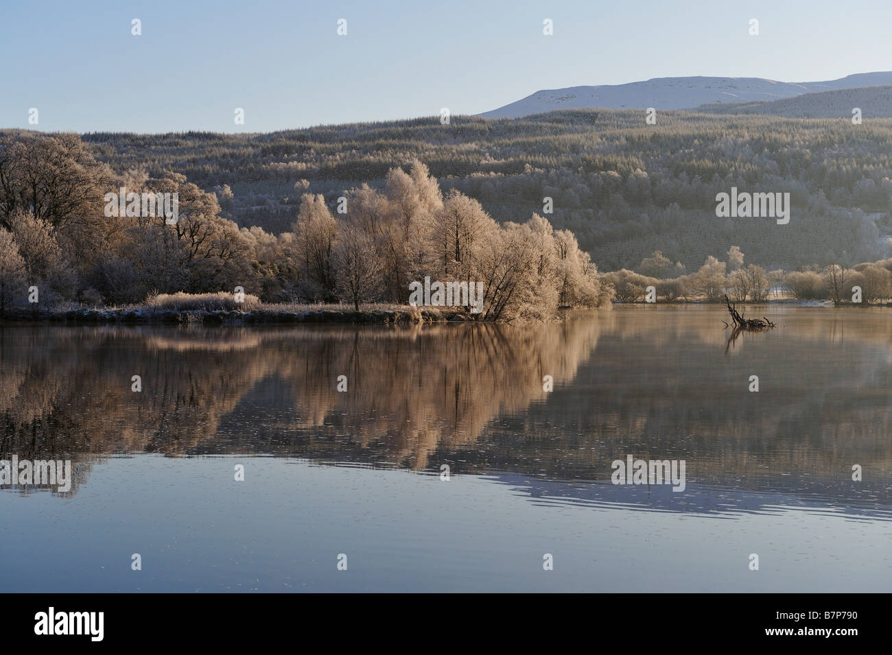 Frozen landscape with tree covered island and distant hills at Loch Tay ...