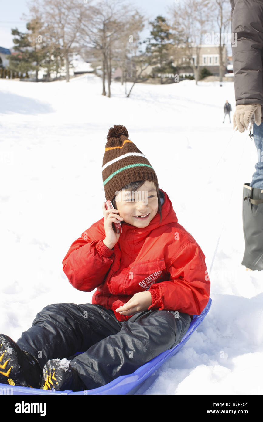 A boy using mobile phone on the sled Stock Photo - Alamy