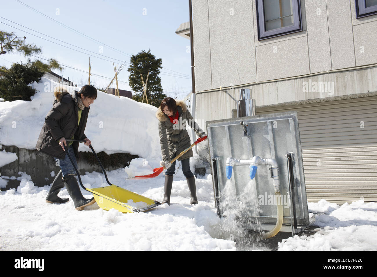 Couple removing snow Stock Photo - Alamy