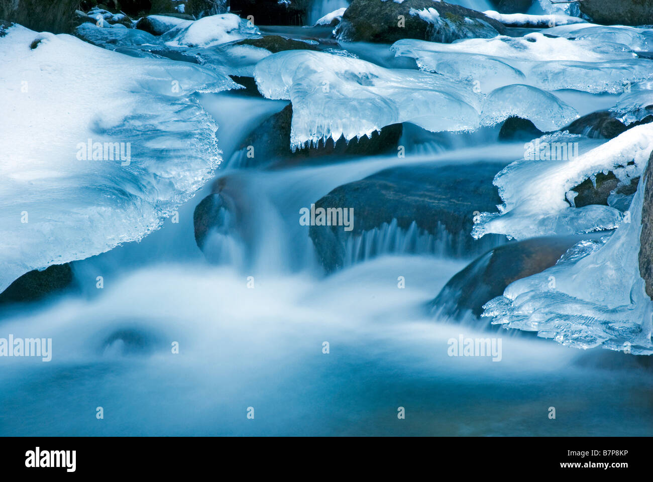 A little stream covered by ice in the mountains Stock Photo - Alamy