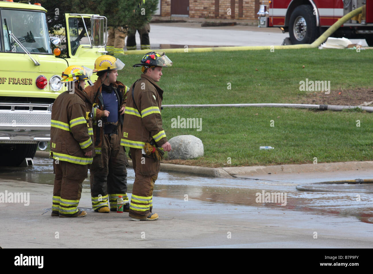 Three firefighters on standby at a fire scene Stock Photo - Alamy