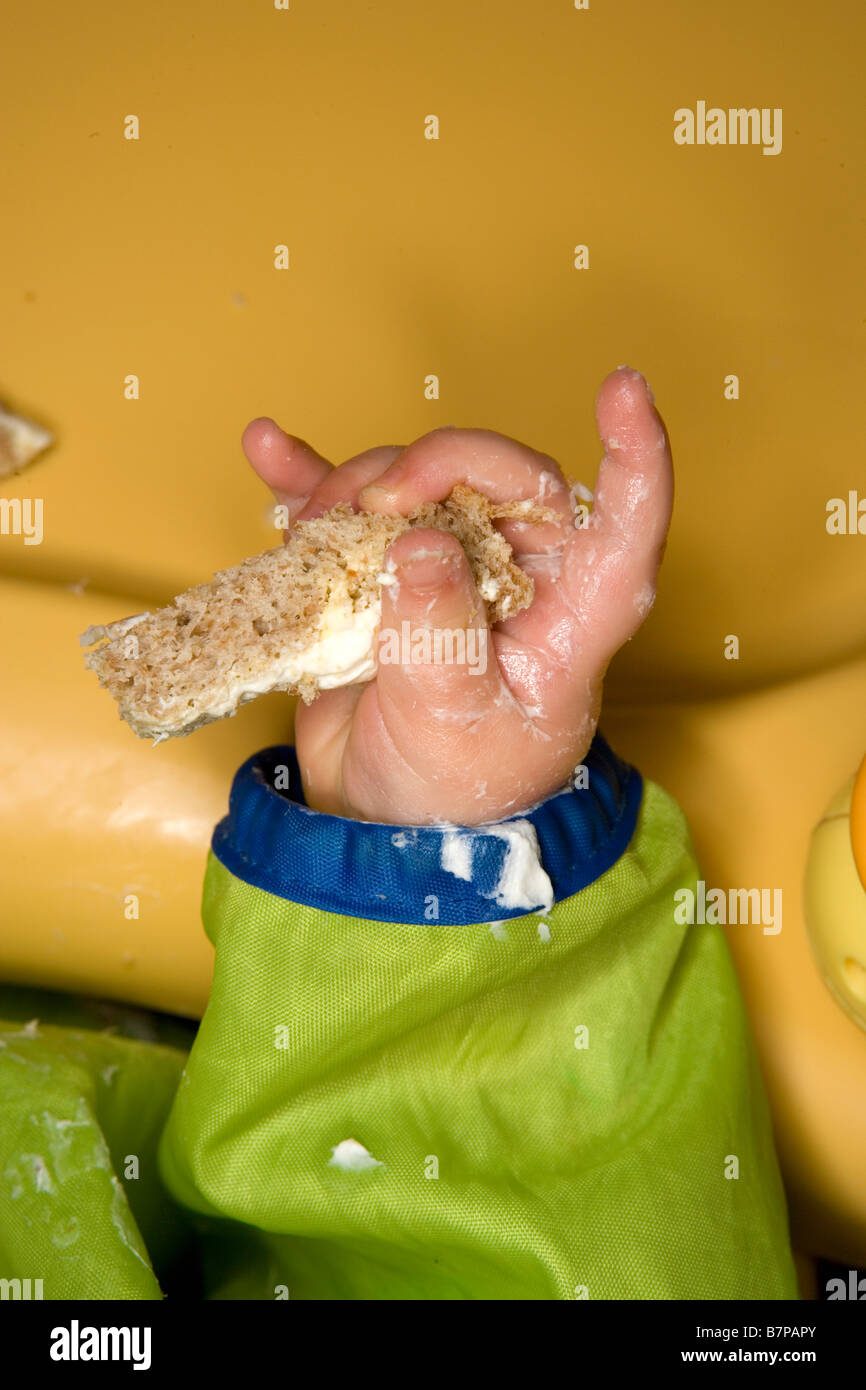a baby holding some bread and butter food Stock Photo - Alamy