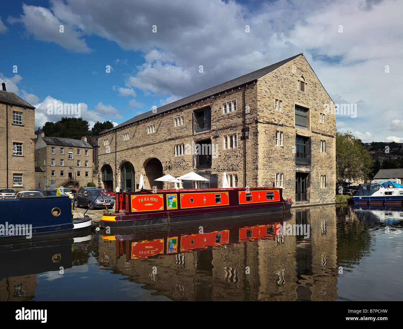 large building set on a canal with canal boat in front and blue sky ...
