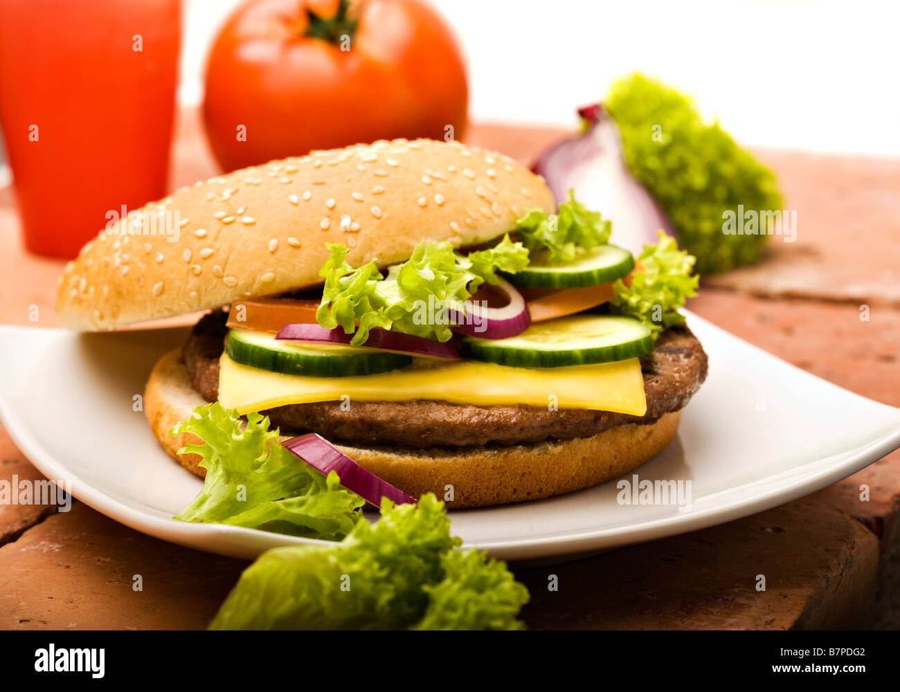 freshly made cheeseburger with tomato, onions, lettuce, cucumber in ...