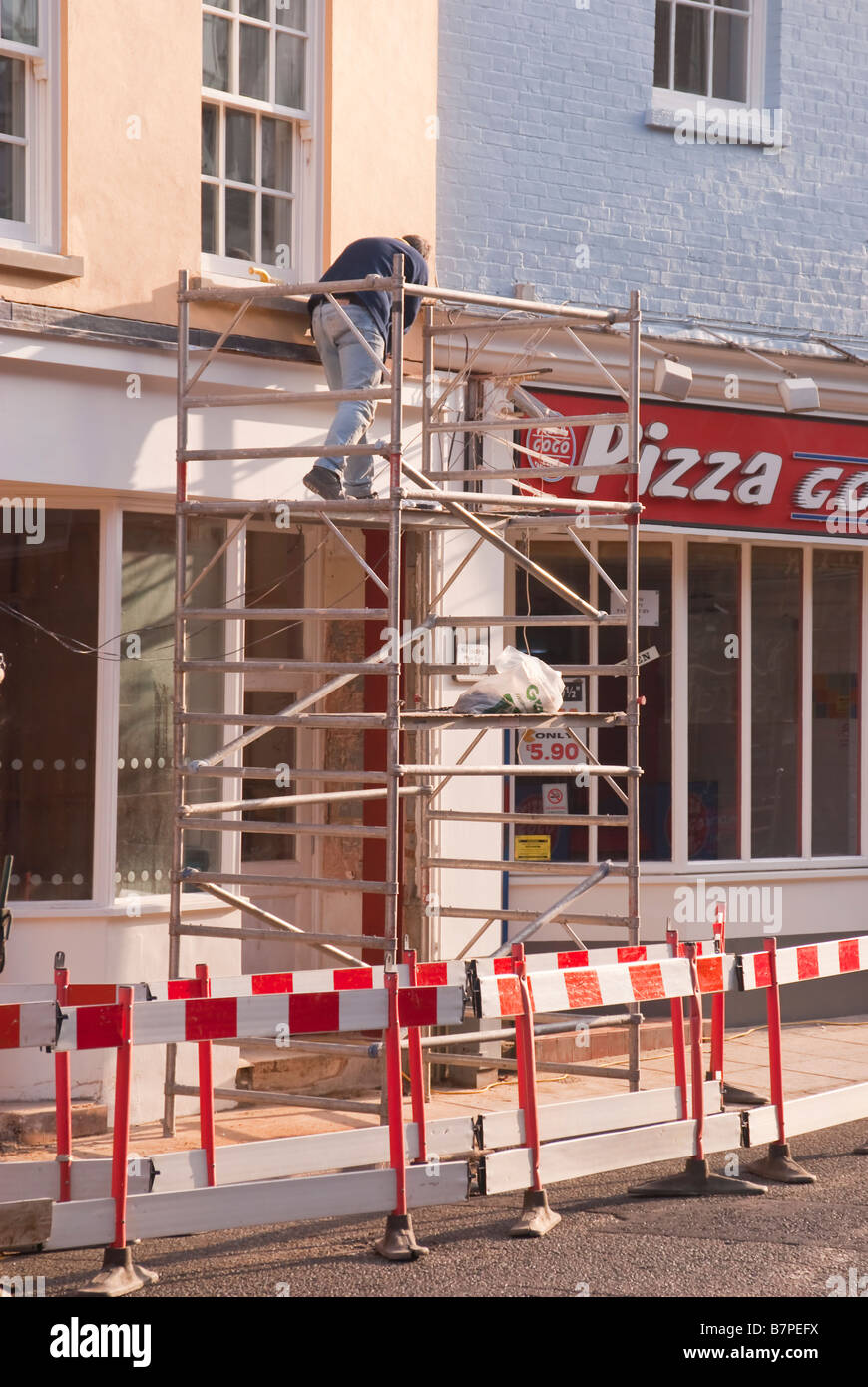 Man working on a building from a tower scaffold with safety barriers ...