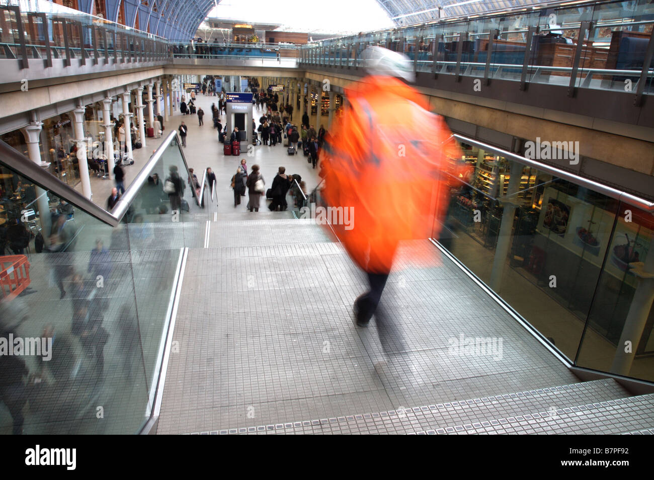 workman with orange jacket going down stairs of Kings Cross station ...