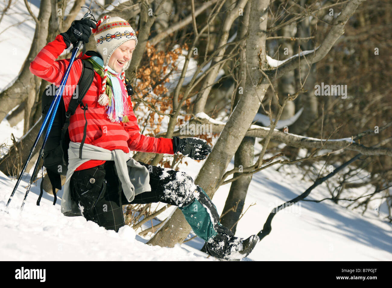 Happy smiling oung woman falling down in high snow slope, frolicking in ...