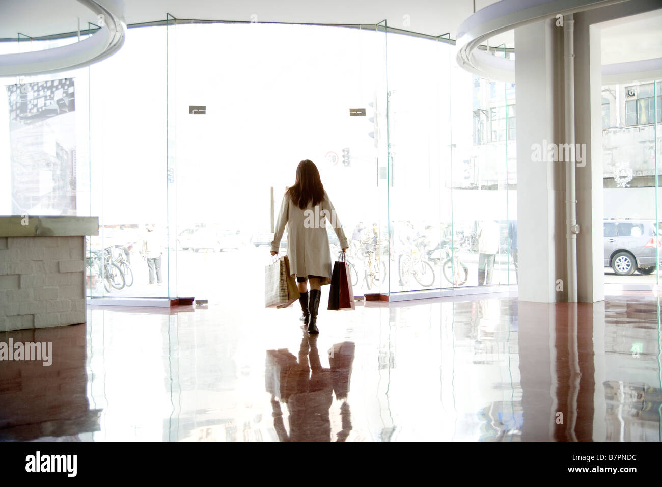 Young woman carrying shopping bags walking toward gate rear view Stock ...