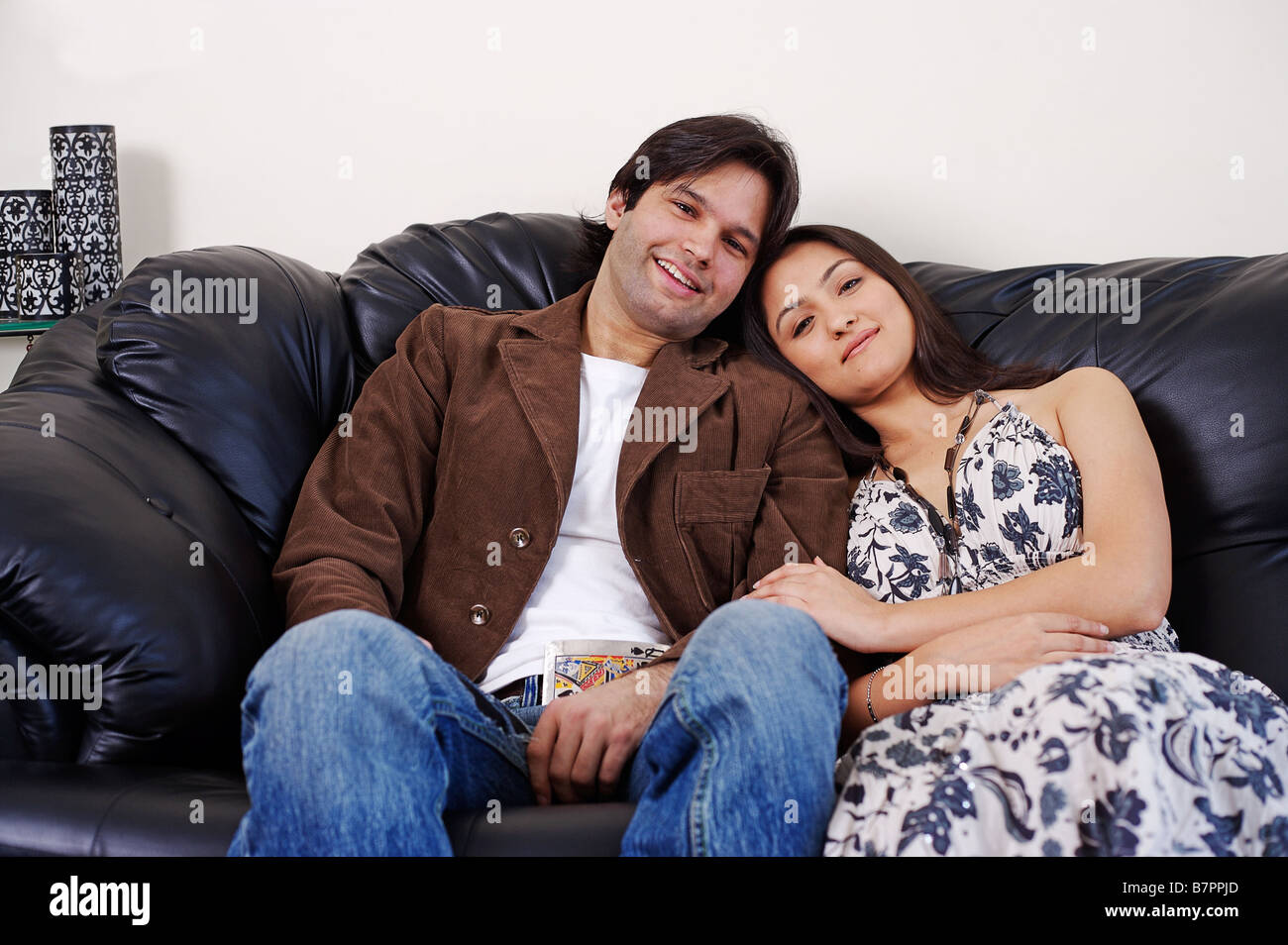 Couple sitting on sofa, smiling Stock Photo - Alamy
