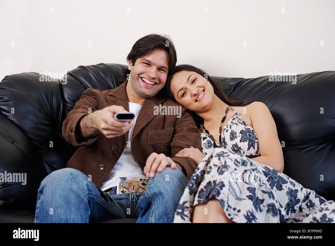 Couple sitting on sofa, smiling Stock Photo - Alamy