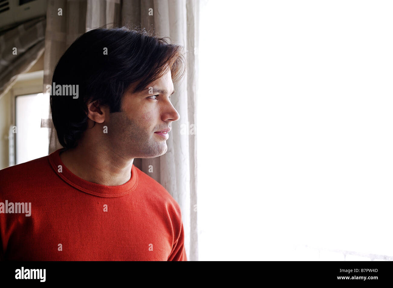 Side view of a man looking through a window Stock Photo - Alamy