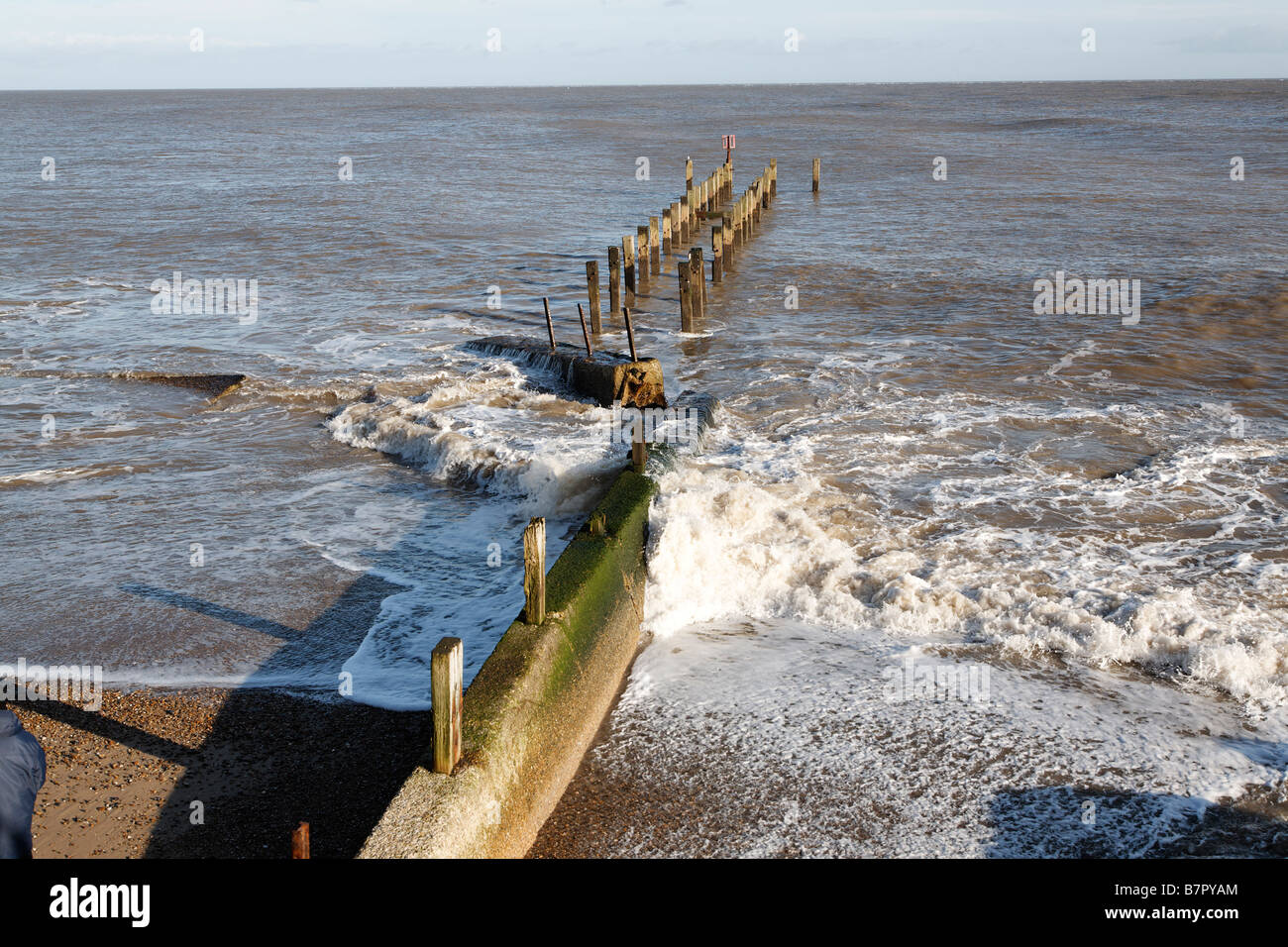Waves crash against wooden groyne Coastal defences Lowestoft Suffolk ...
