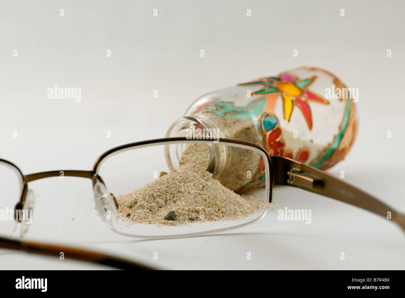Toppled colourful bottle, spilling sand as seen through glasses Stock ...