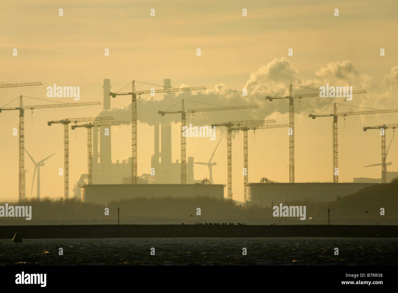 Many cranes and chimney pouring plumes smoke silhouette evening sky ...