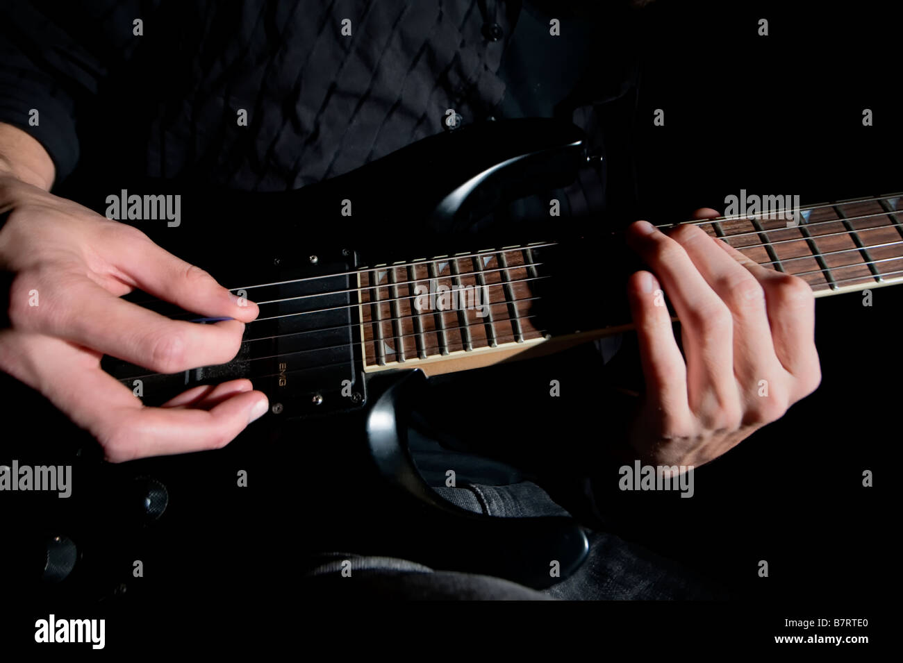 Hands on a black guitar Stock Photo - Alamy