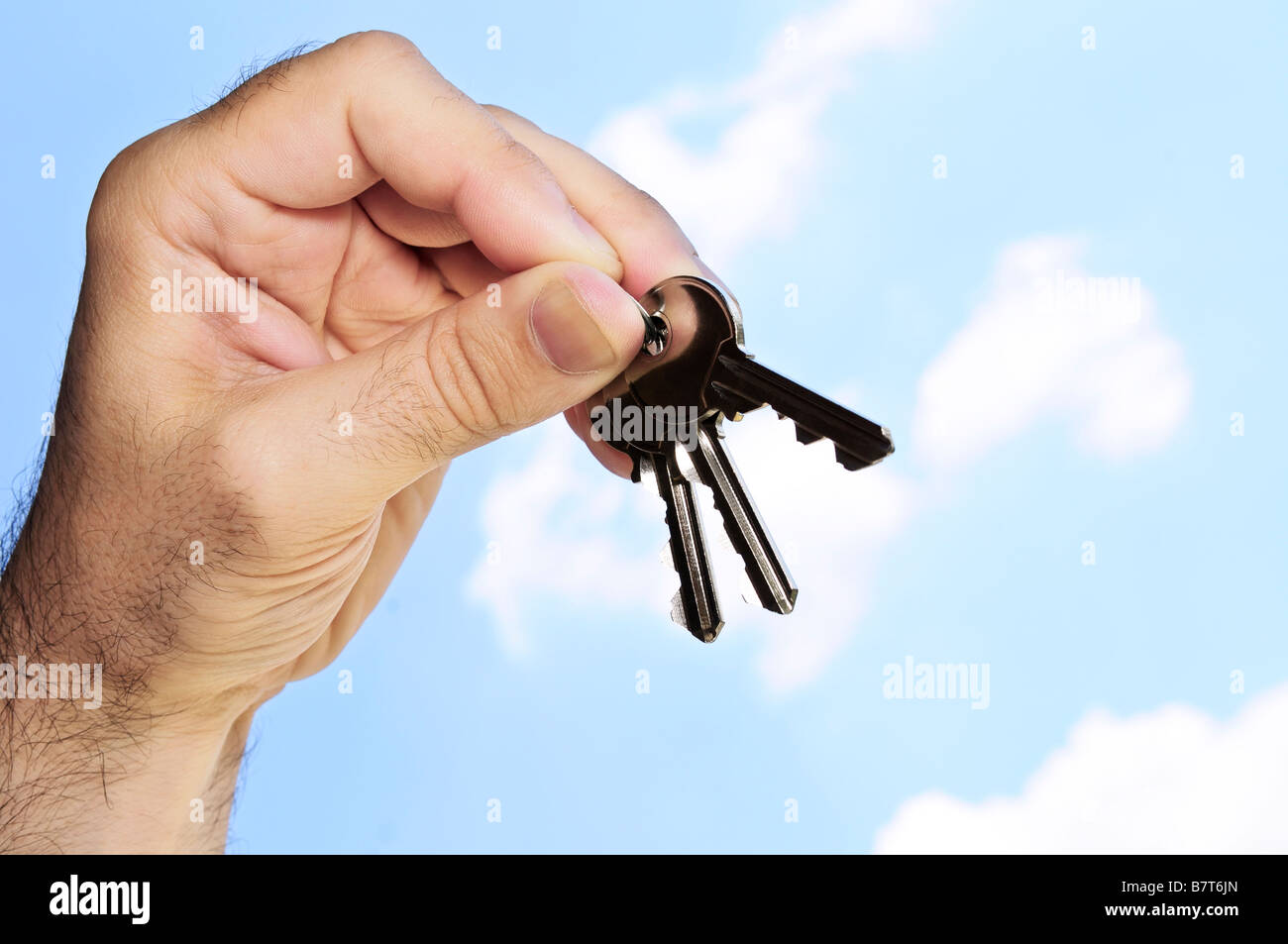 Man s hand holding house keys on blue sky background Stock Photo - Alamy