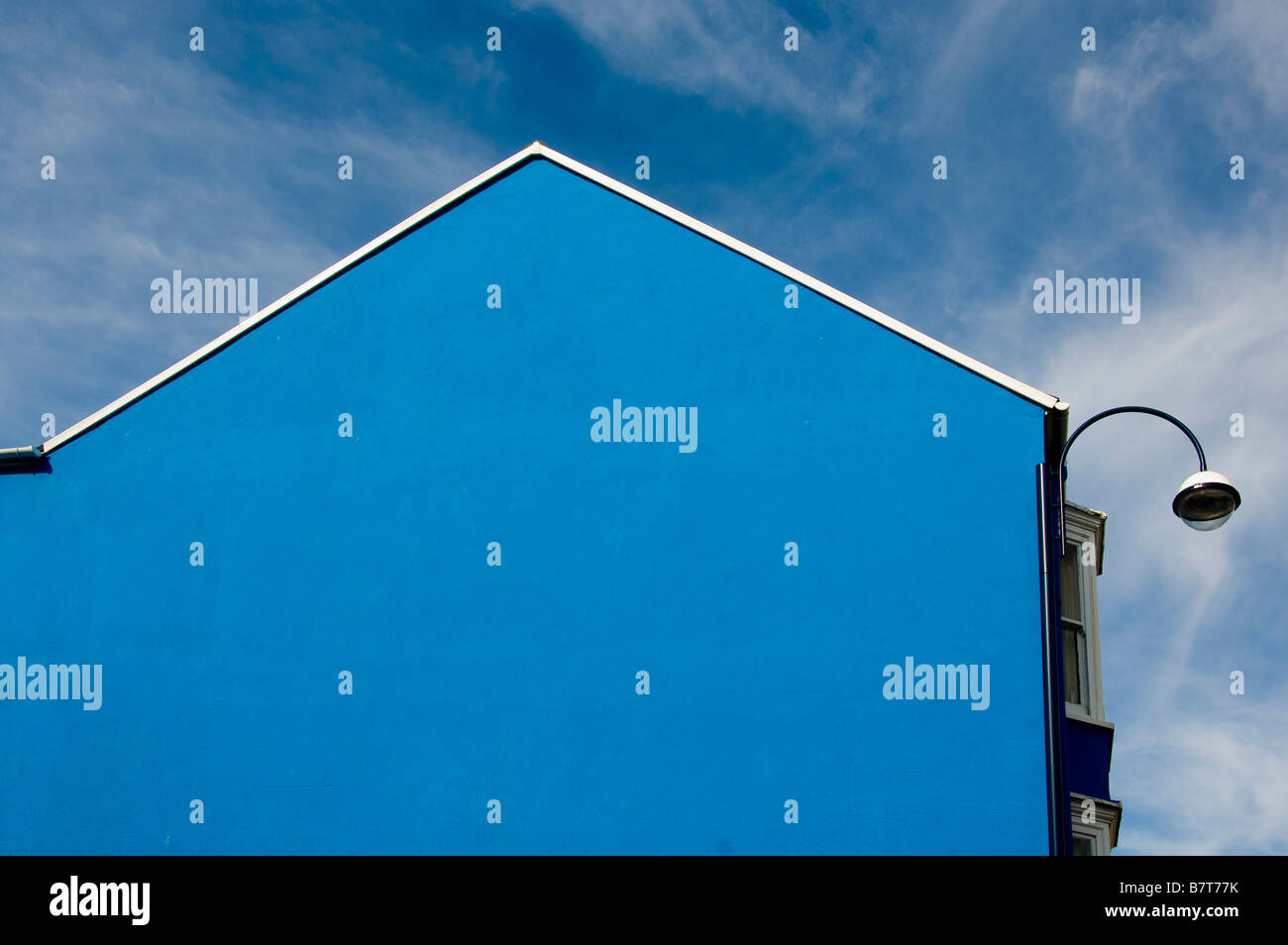 Blue rendered gable end on a UK terrace house, seen against a blue sky ...