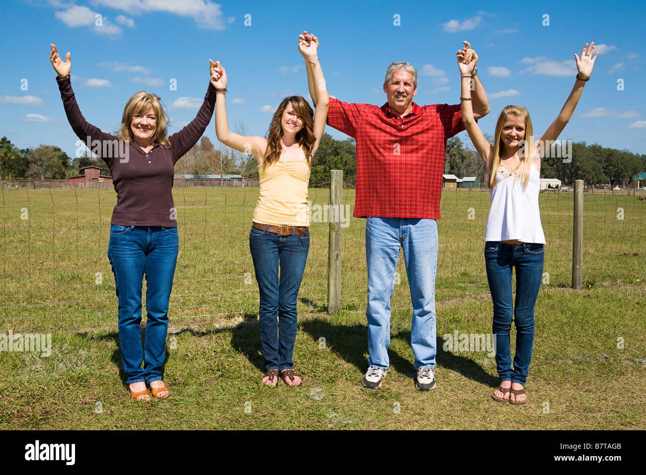 Beautiful family outdoors on their farm holding hands and raising their ...