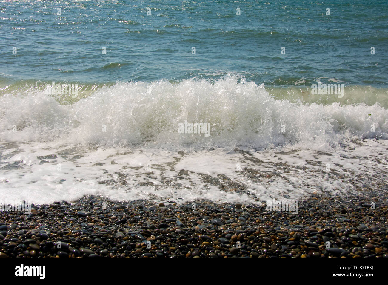 Waves crashing onto shingle beach Stock Photo - Alamy