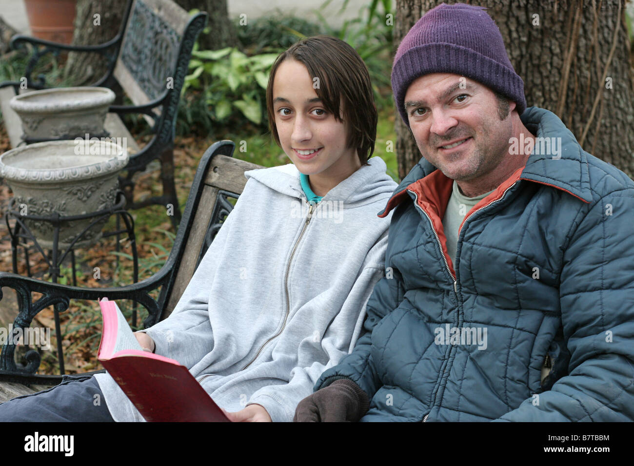 A teen aged boy reading the sharing the bible bible with a homeless man ...
