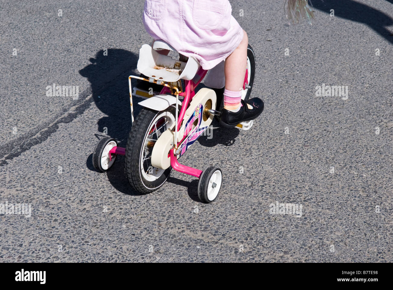 Young girl riding a bike with support wheels, Howth Peninsula, Dublin ...