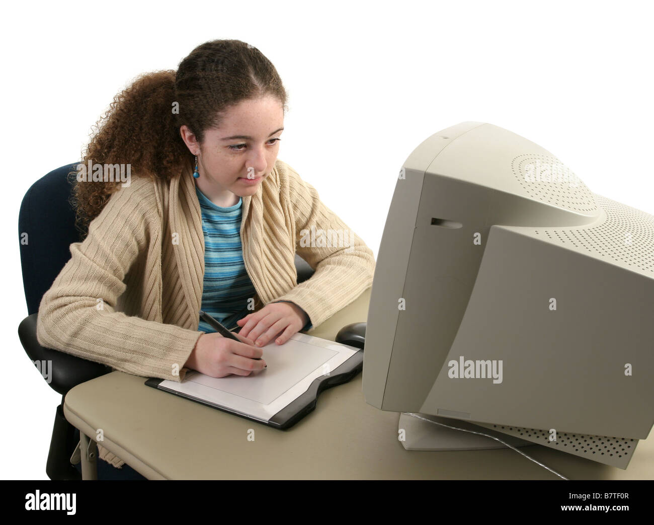 A teen girl concentrating as she draws on a computer graphics tablet ...