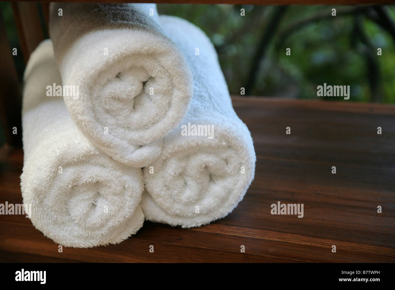 Three rolled white towels on a wooden table Stock Photo - Alamy
