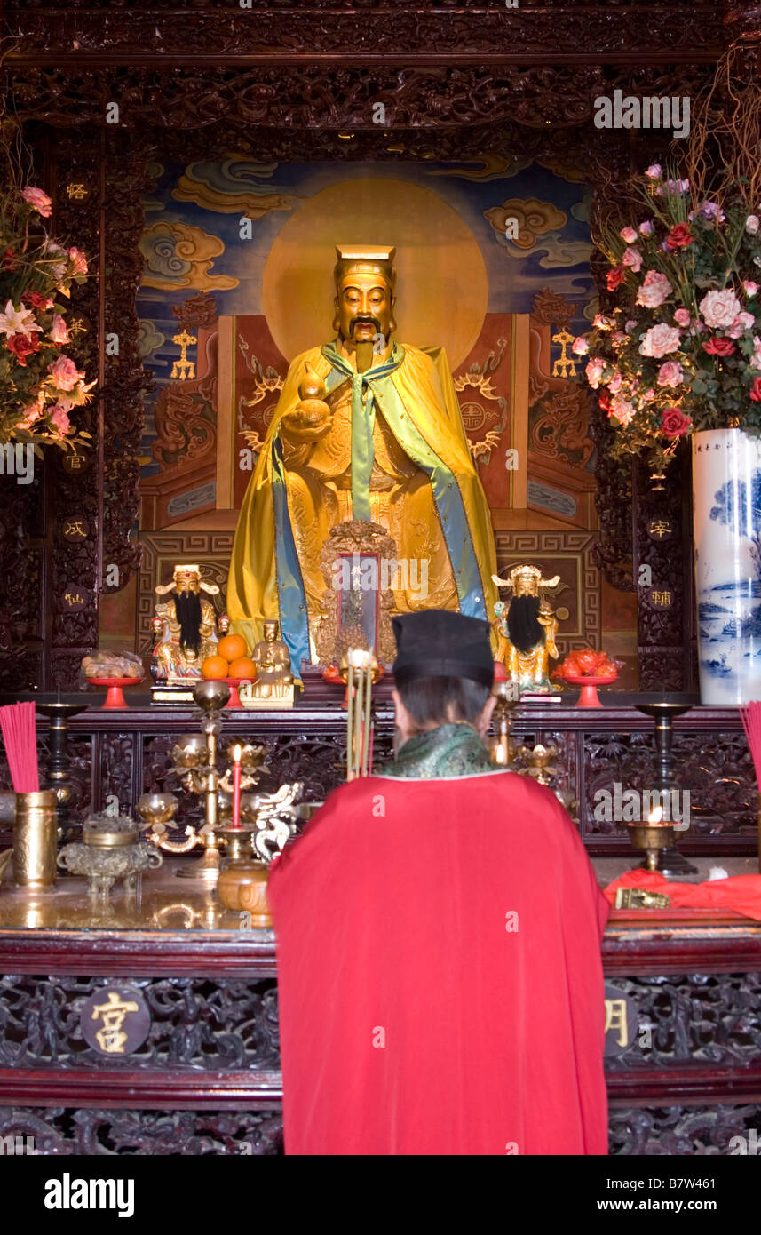 Tao monk lights candles at the shrine of the god called Xian Zu Dian at ...