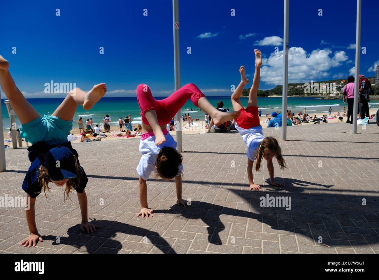Three children (two 10 year olds, one 6 year old) doing handstands on ... Three children (two 10 year olds, one 6 year old) doing handstands on ...