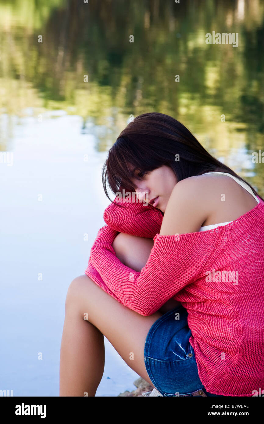 Young thoughtful woman against water background Stock Photo - Alamy